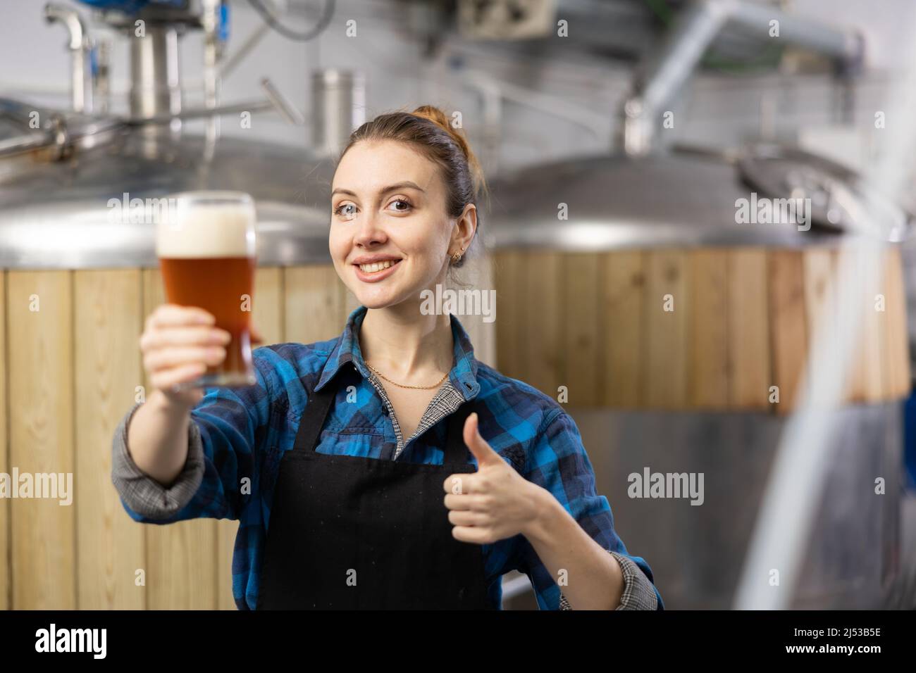 Female brewer showing thumbs up while holding glass of beer Stock Photo ...