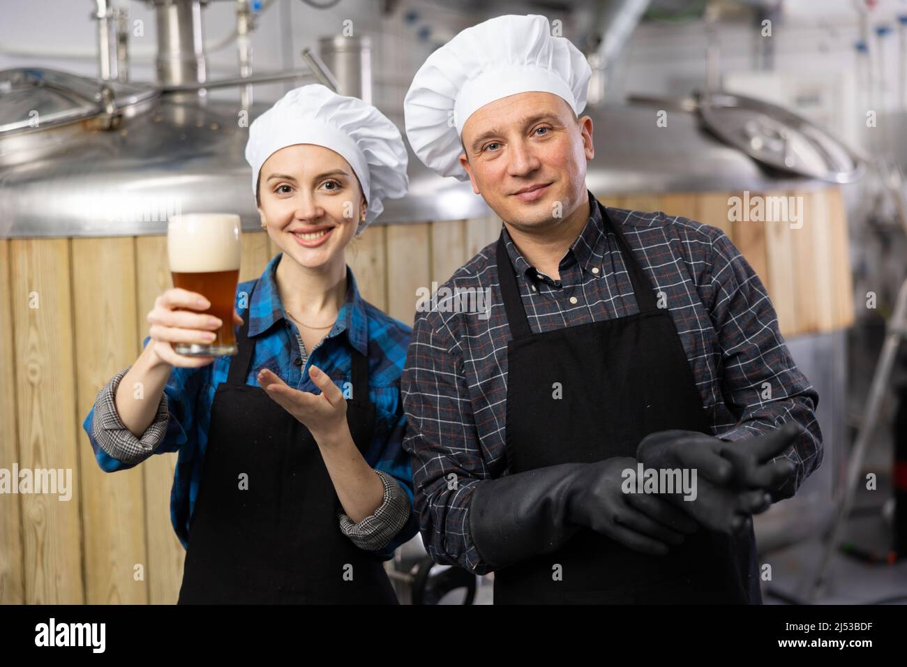 Positive brewmasters presenting beer in brewery Stock Photo - Alamy