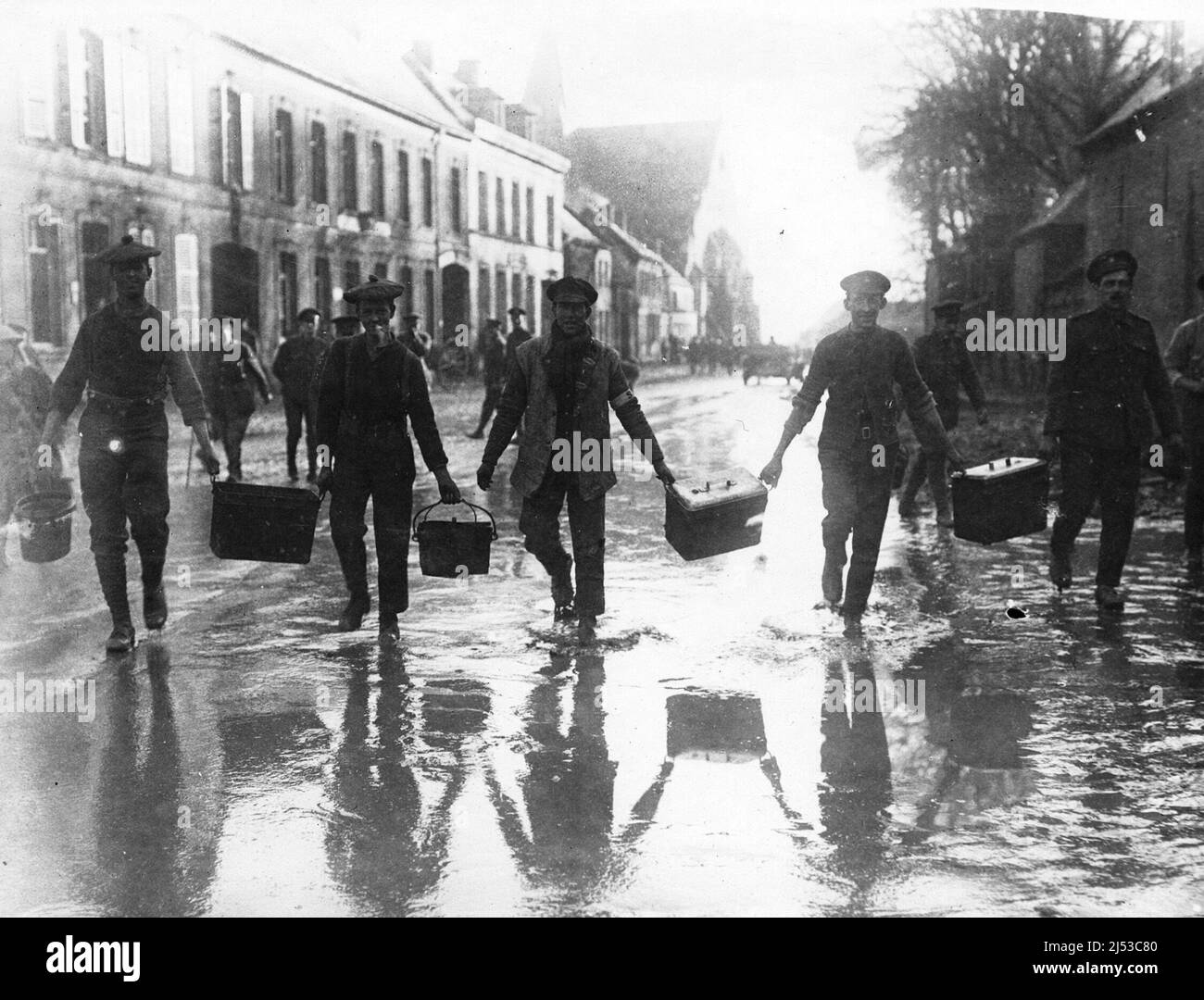 Soldiers carrying boxes of hot food in a muddy street in France Stock ...