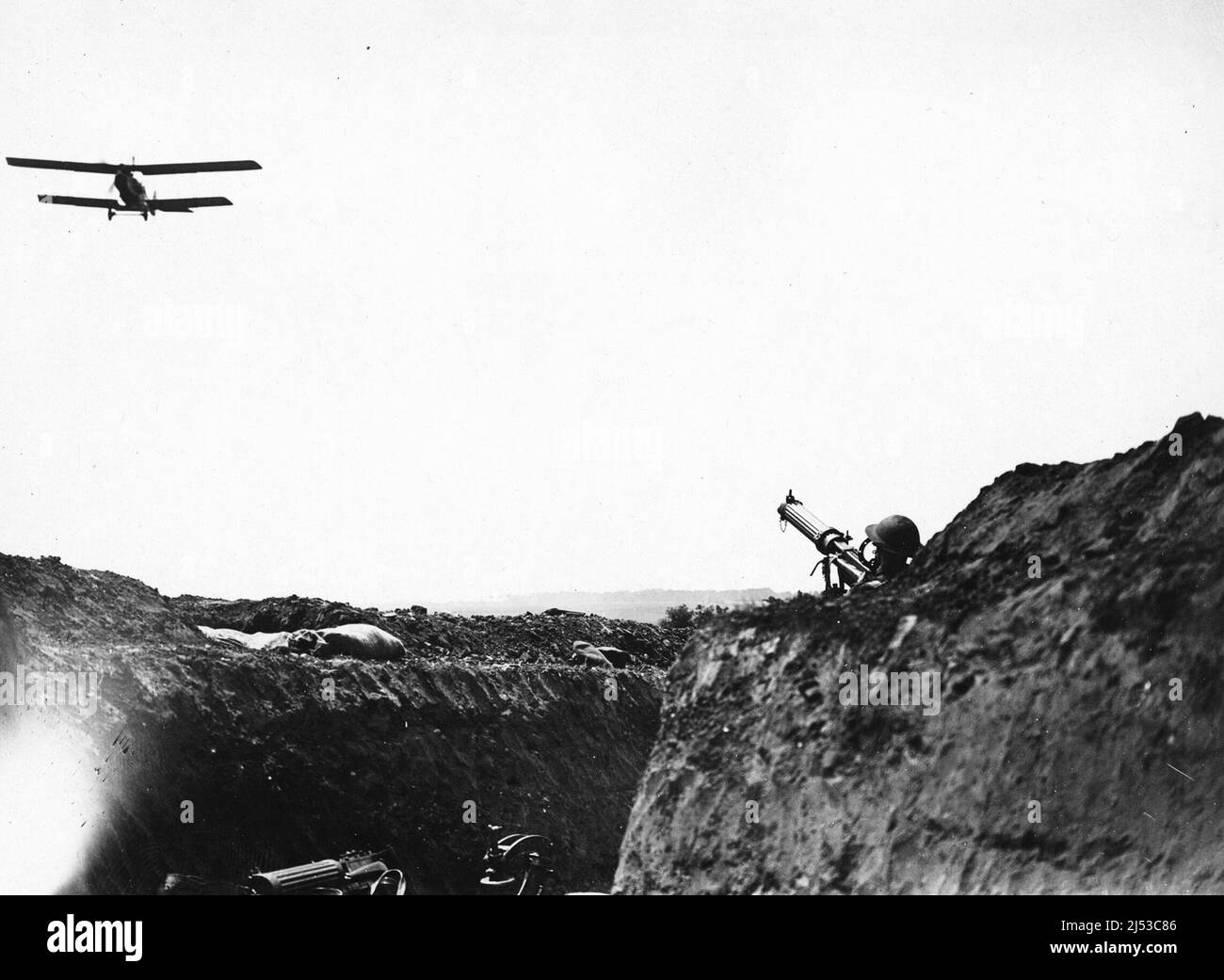 A Vickers machine gun in the trenches aiming at a low flying biplane ...