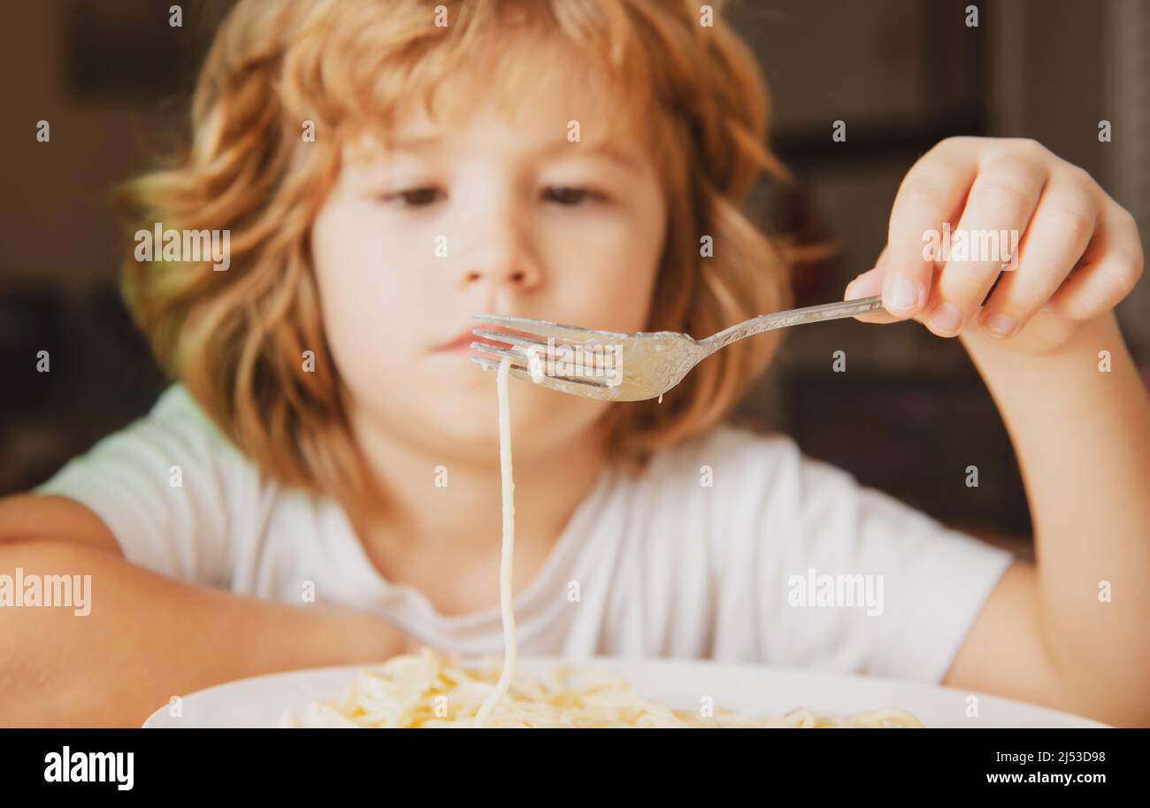 Portrait of a cute child boy eating pasta, spaghetti. Close up ...
