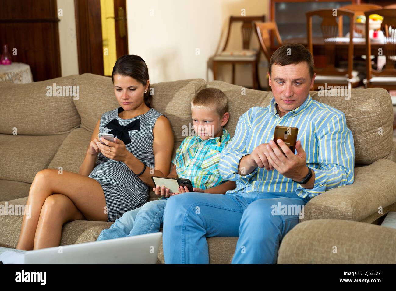 Young family and his son using phones at home interior Stock Photo - Alamy