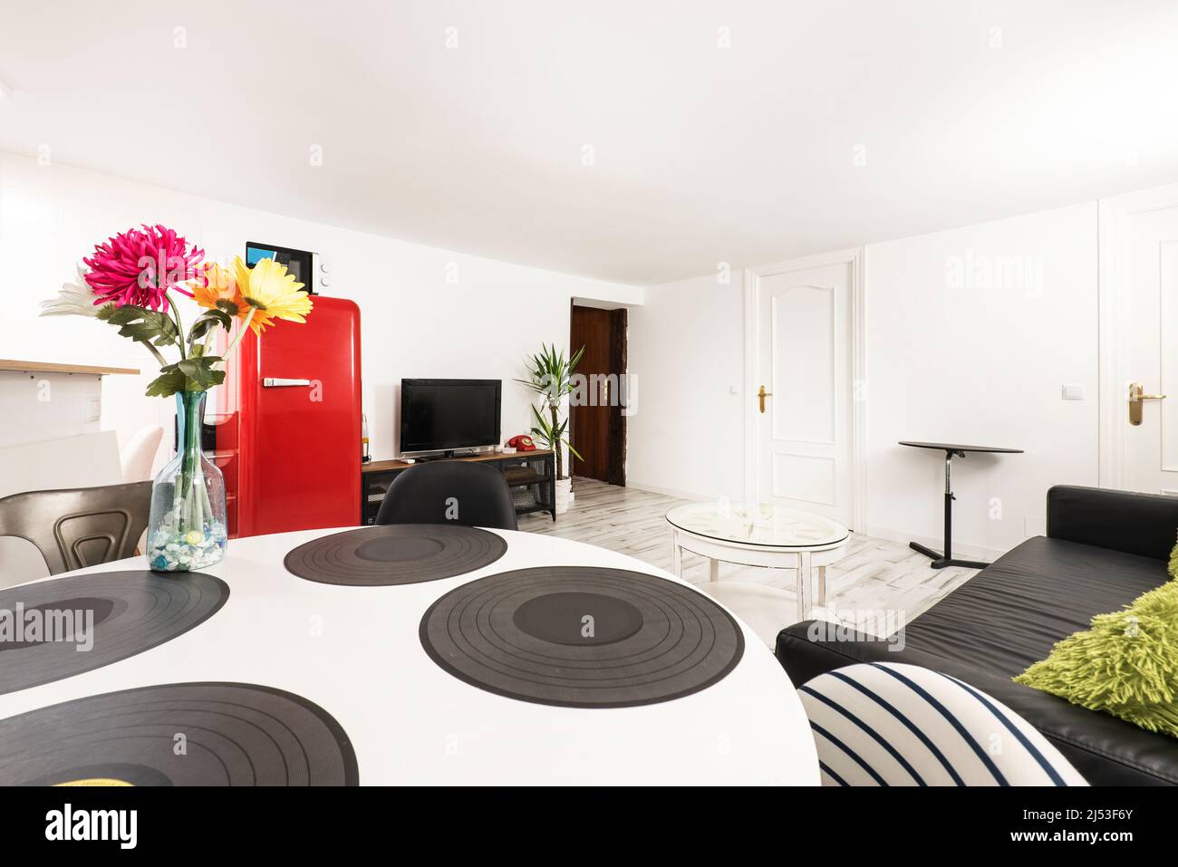 Living room with circular wooden dining table, three-seater black ...