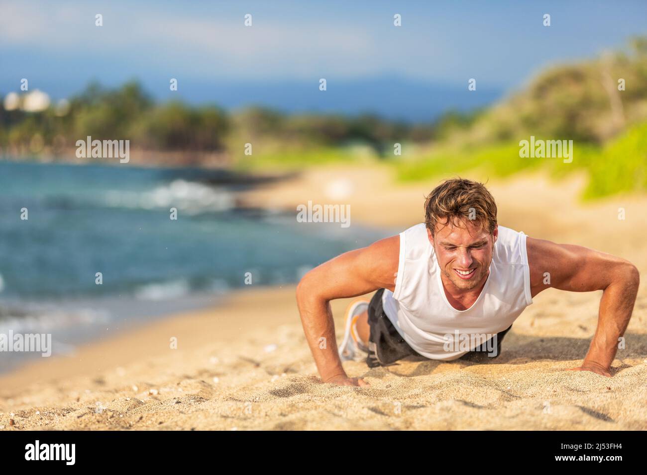 Fitness exercise man training arms doing push ups outdoor on beach ...