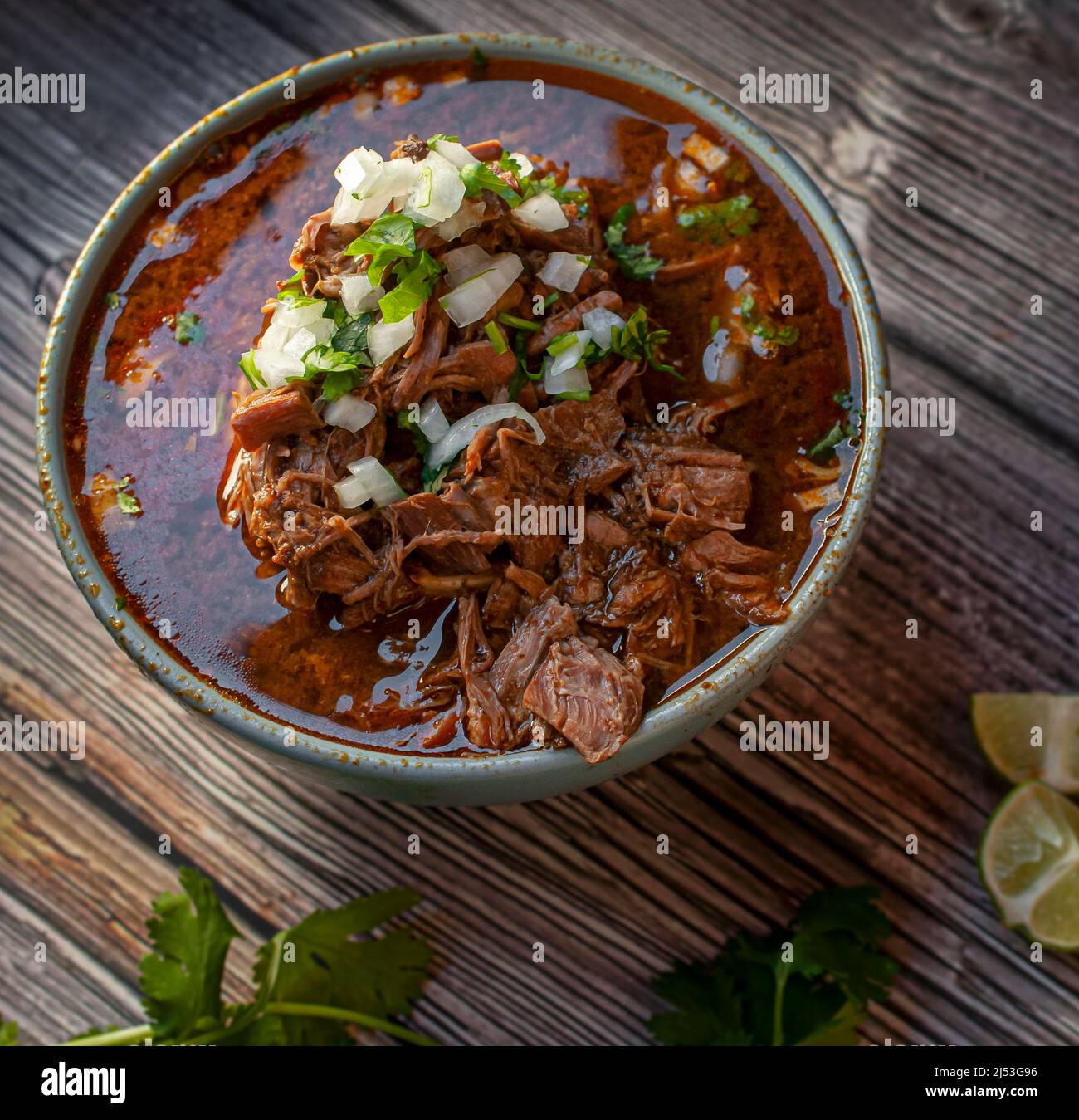 A bowl of BIRRIA or BARBACOA, a traditional Mexican dish with lemons ...