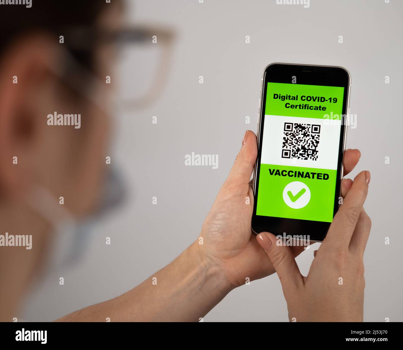 The doctor holds a smartphone with a QR code about the vaccination ...