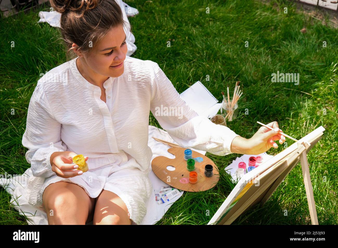 Artist painting on the easel outdoors in the garden. Open air outdoor ...