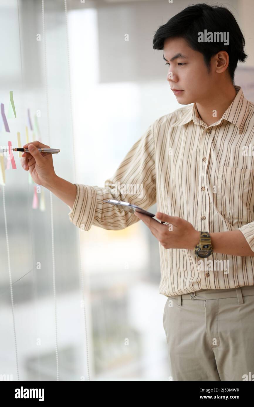 Portrait of Asian young businessman taking his marketing ideas in a ...