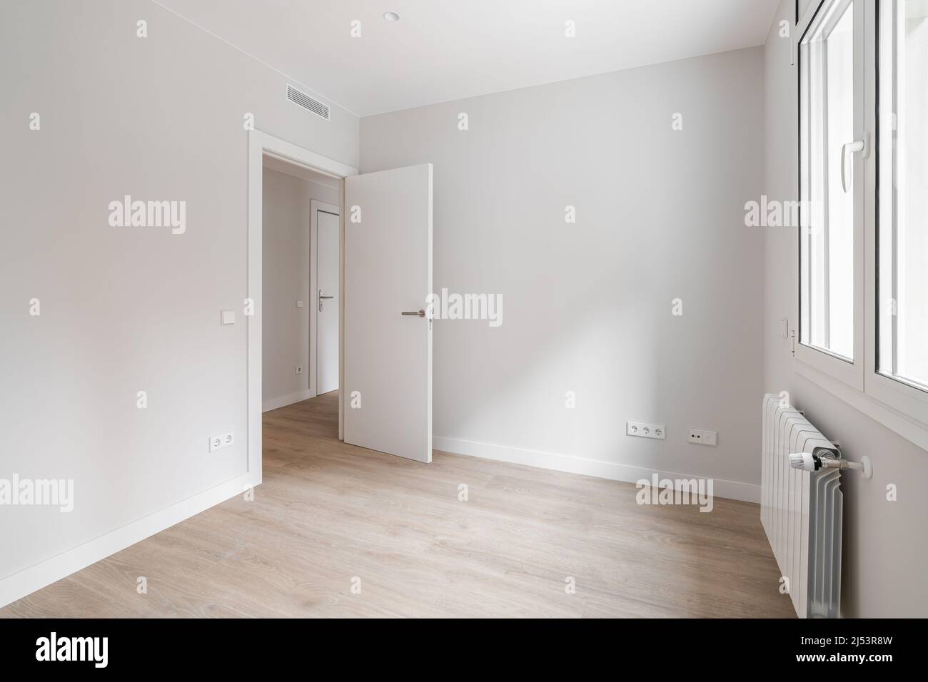 Empty room with door, window, and heating radiator in a white interior ...