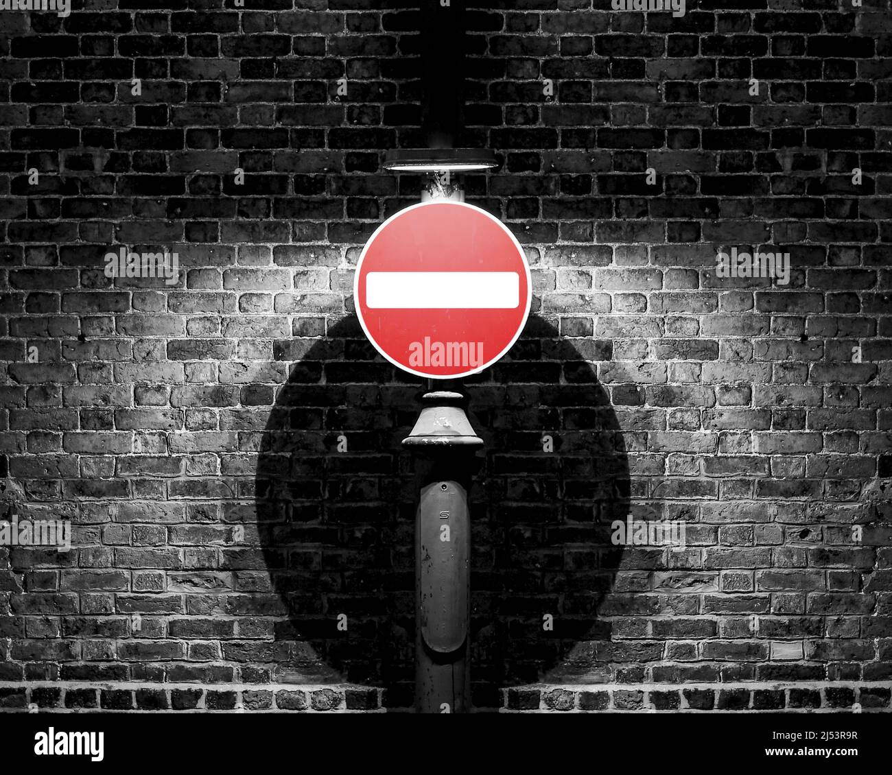 A stop sign in front of a brick wall at night symbolising the end of ...