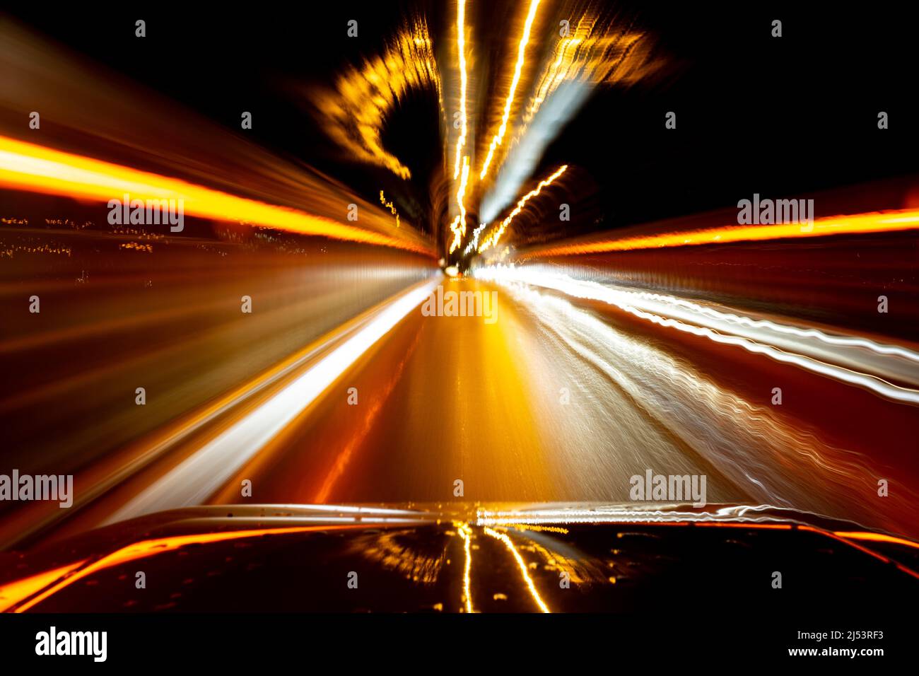 Blurred street lighting through the windscreen of a moving car giving ...
