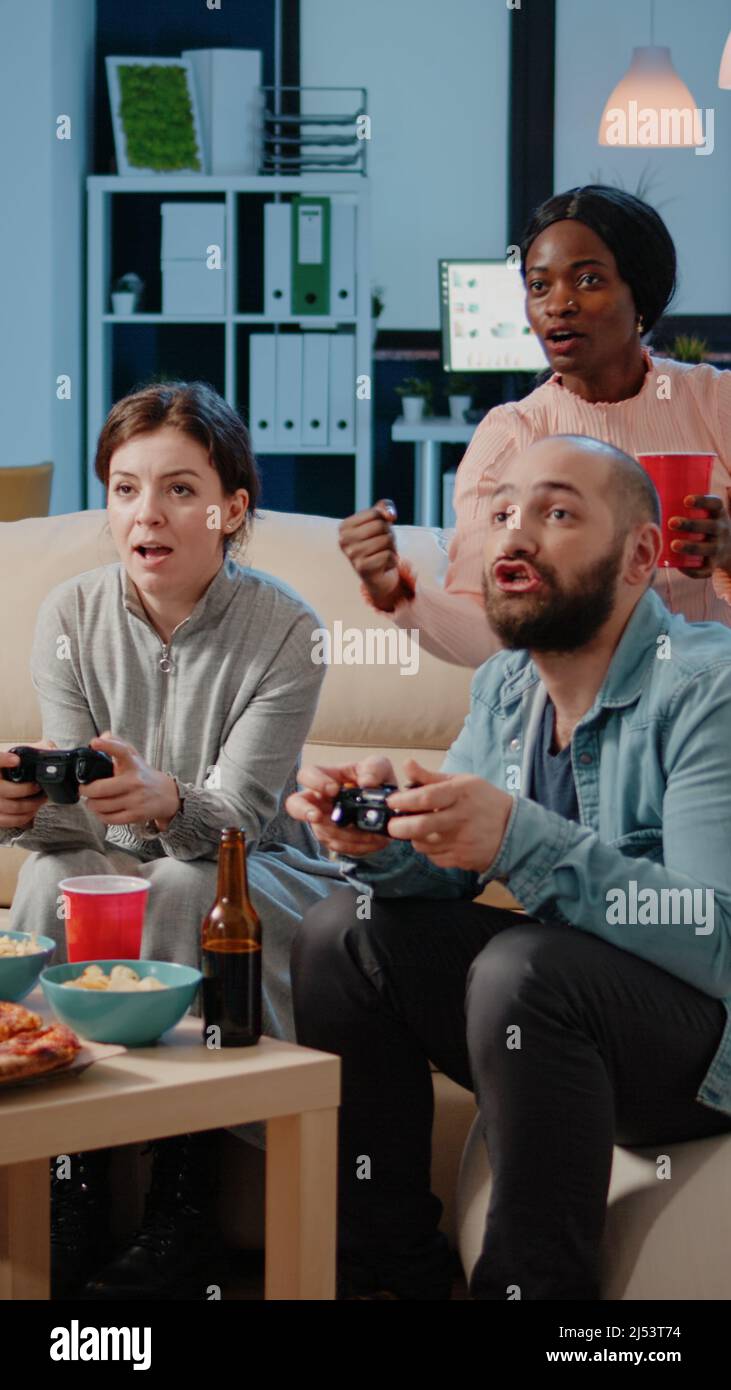 Diverse group of workmates using joysticks to play video games on ...