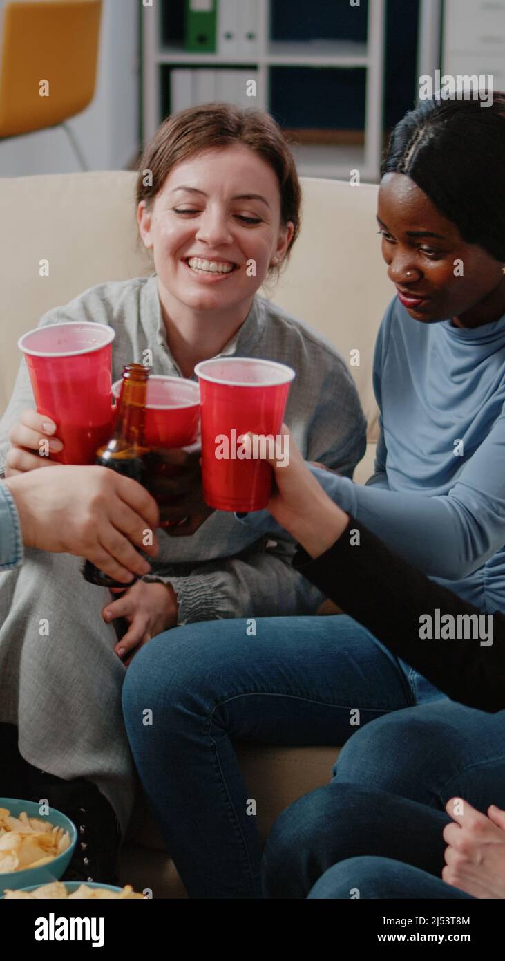 Coworkers clinking cups and bottles to enjoy leisure after work. Happy ...
