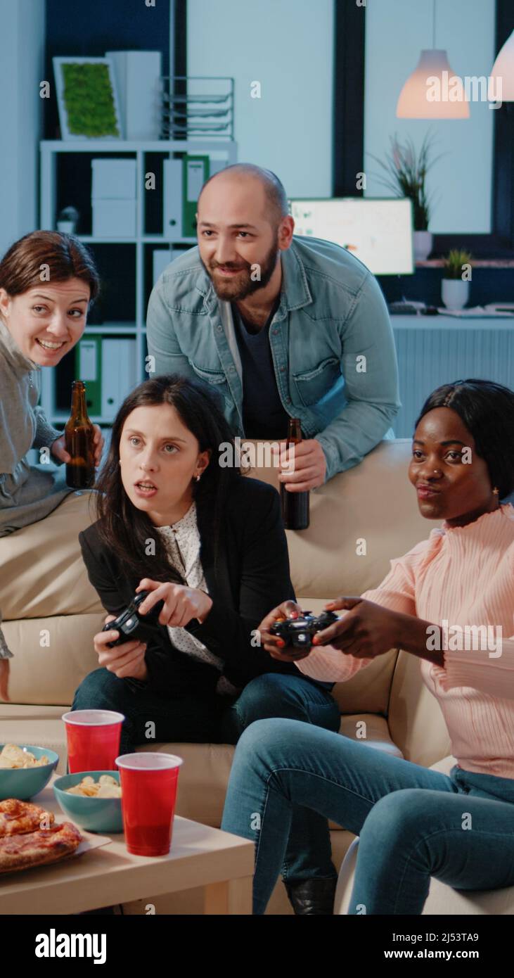 Multi ethnic group of people using joysticks to play video games on tv ...