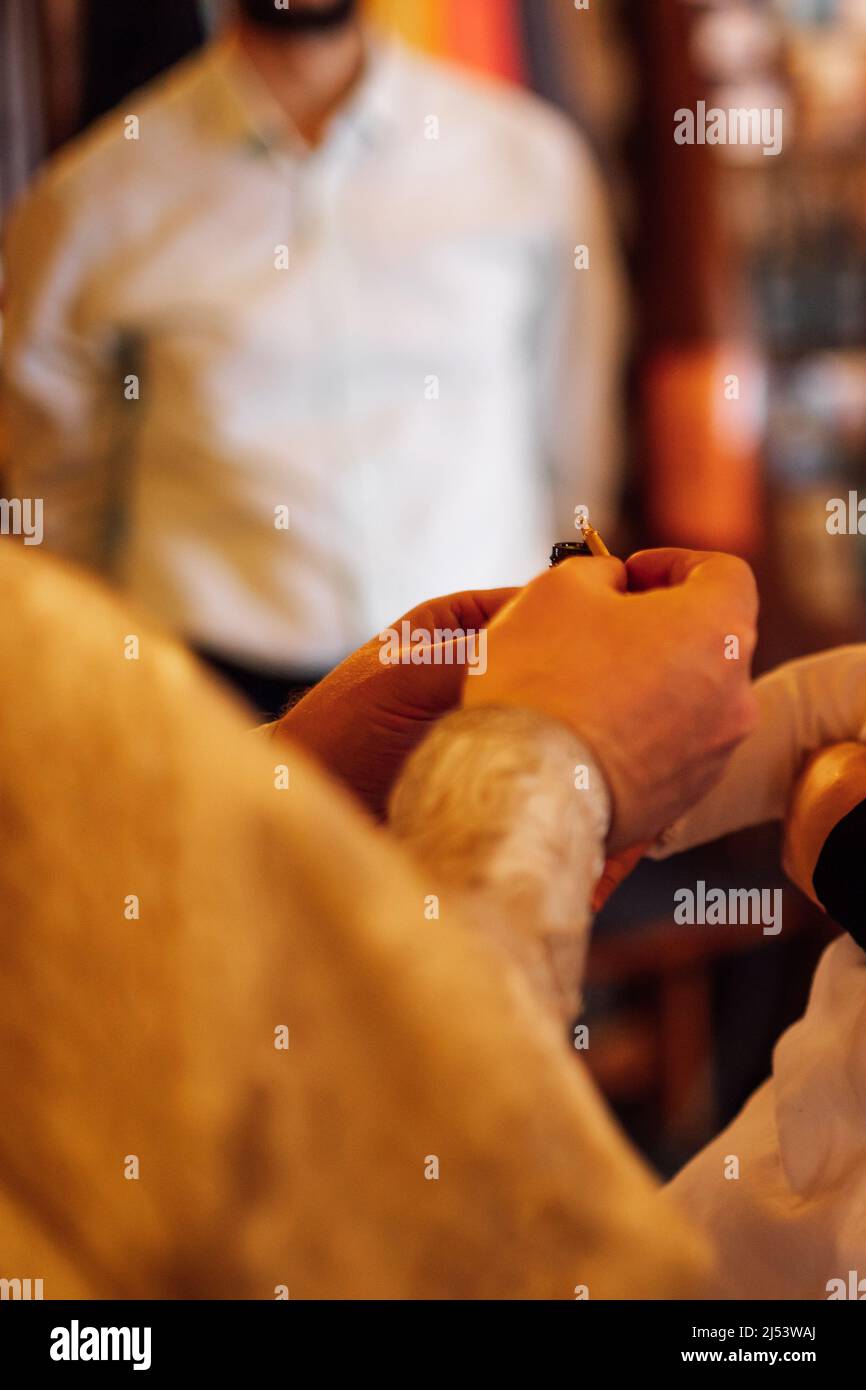 Cropped photo of priest in ceremonial cassock hold bottle with holy oil ...