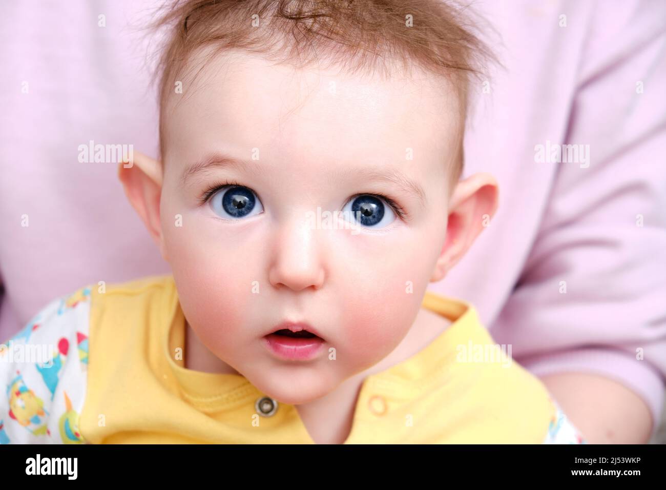 Surprised infant baby boy with big blue eyes and disheveled hair in his ...