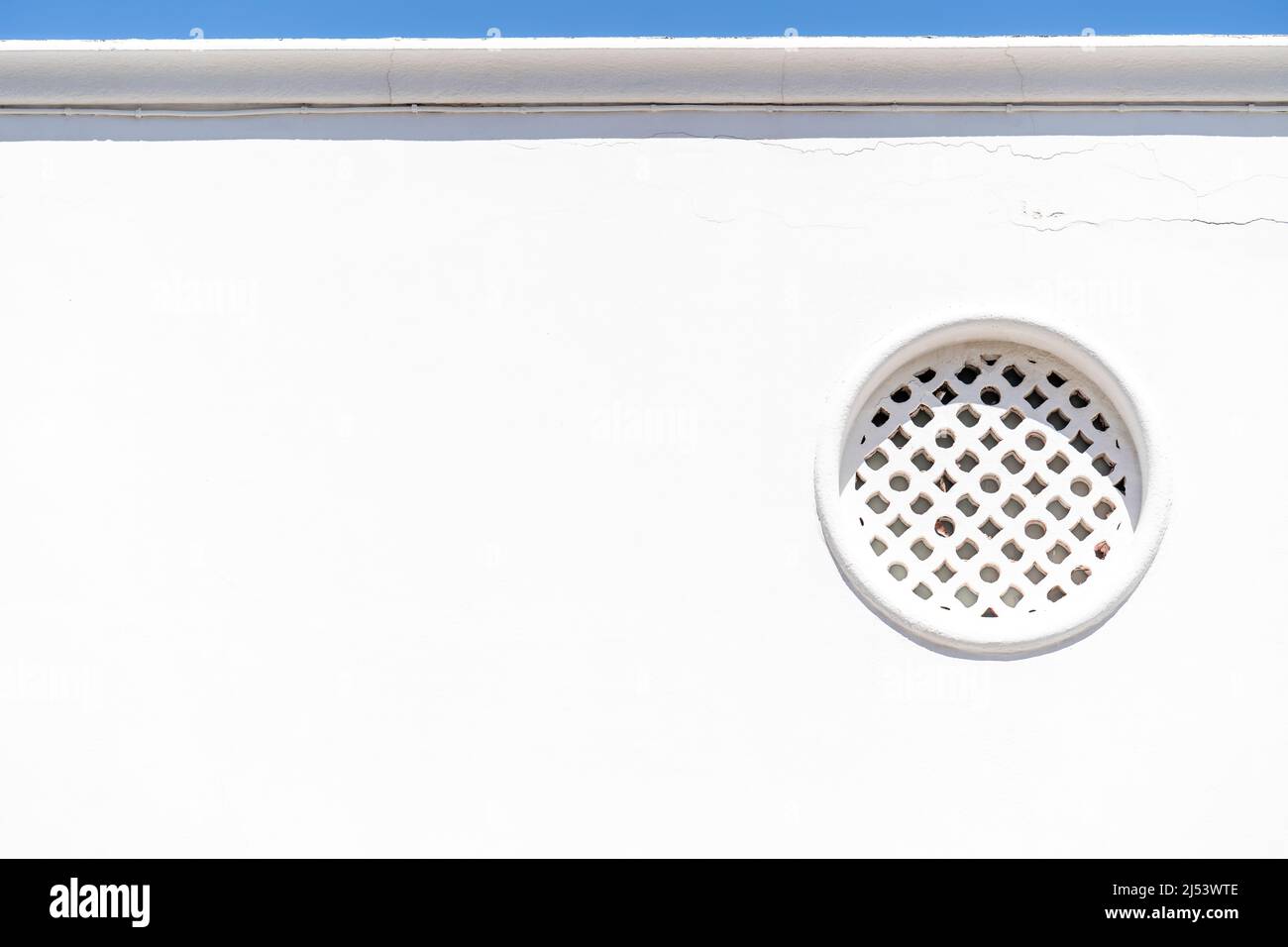 Minimalist Art Decorative circular window on a white wall and a small ...