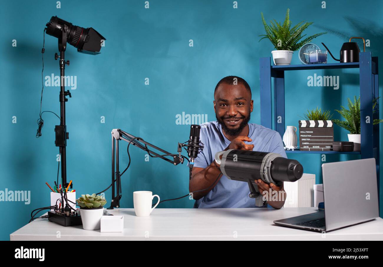 Vlog reviewer presenting new model video light sitting at desk with ...