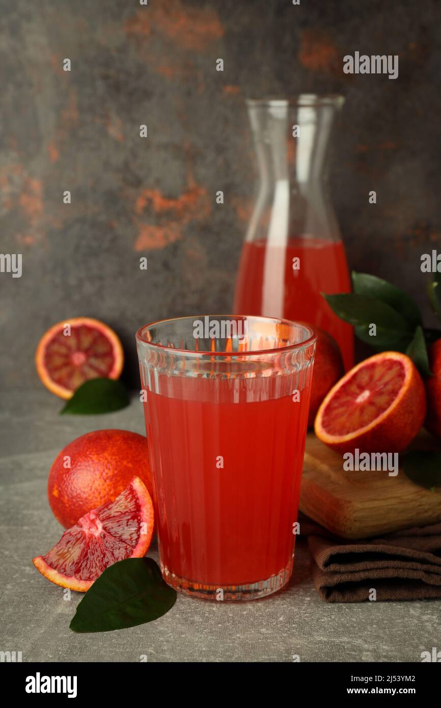Concept of fresh drink with red orange juice on gray textured table ...