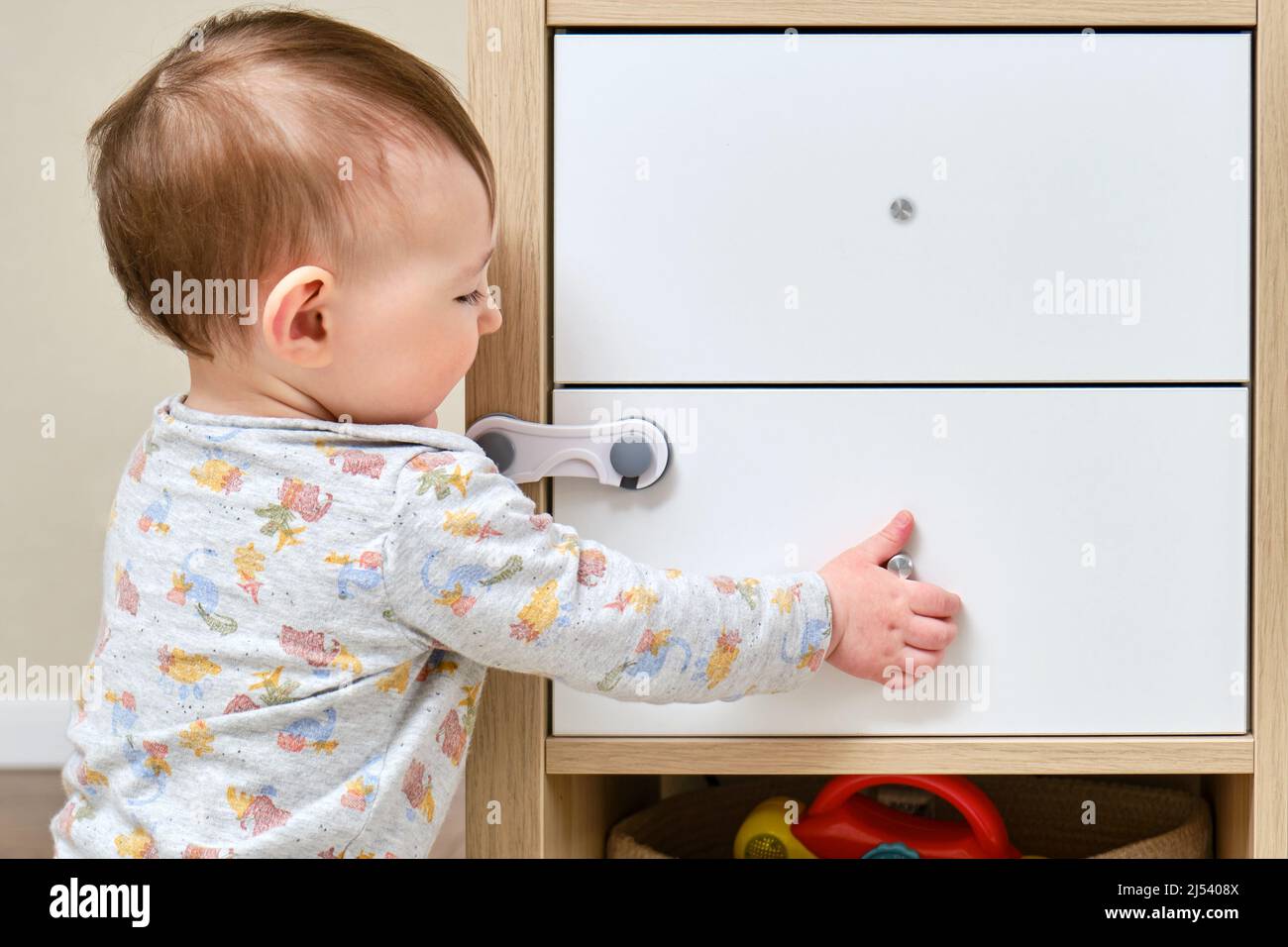 Toddler baby boy rips off a cabinet drawer with his hand. The child ...