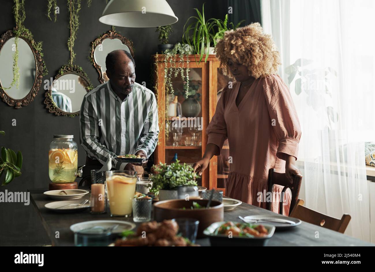 African family setting the table for holiday dinner together in dining ...