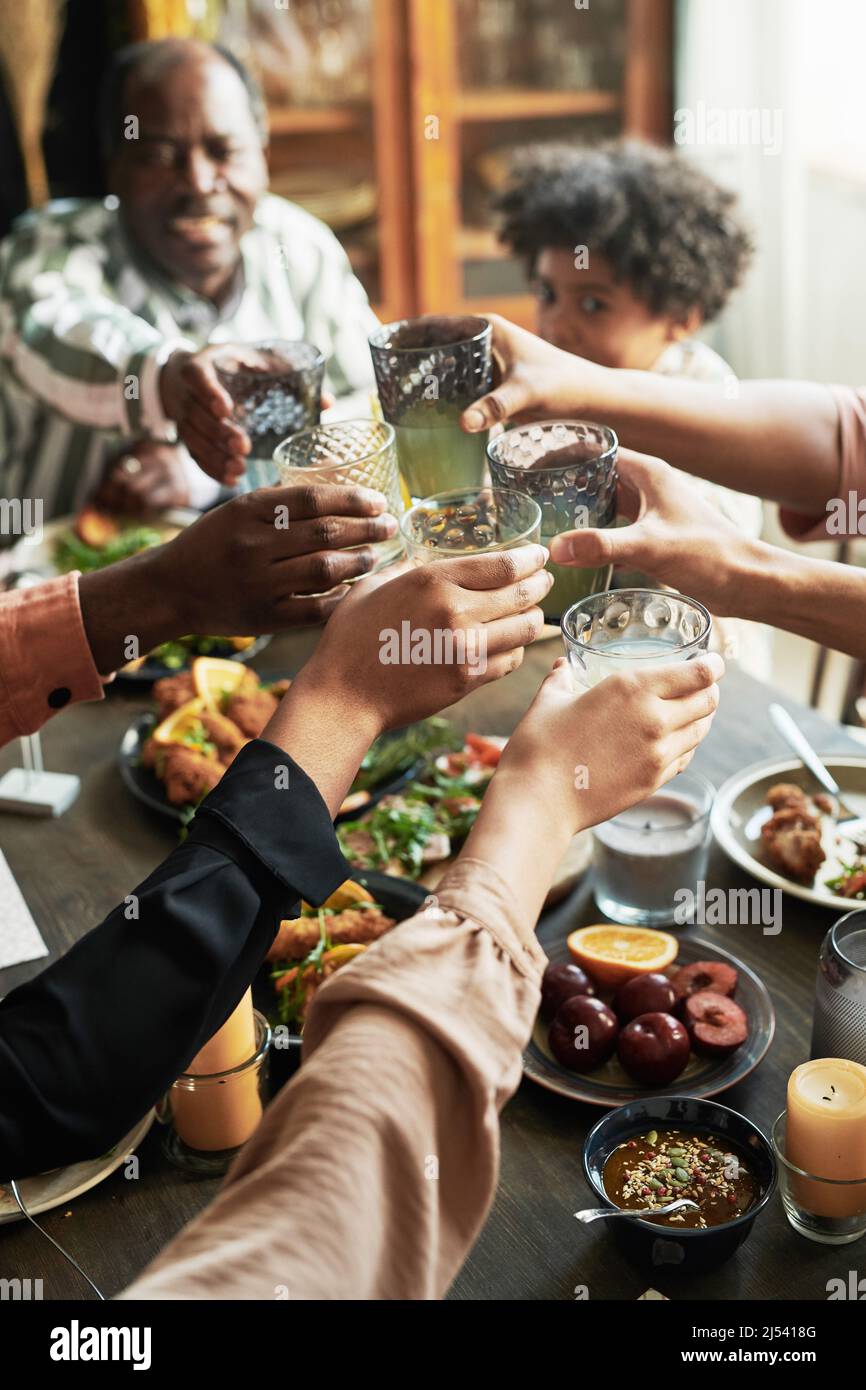 Close-up of family toasting with glasses of drinks while sitting at ...