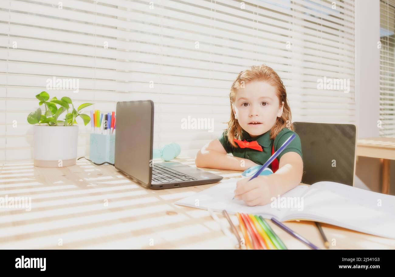 Cute pupil writing at notebook in classroom at the elementary school ...
