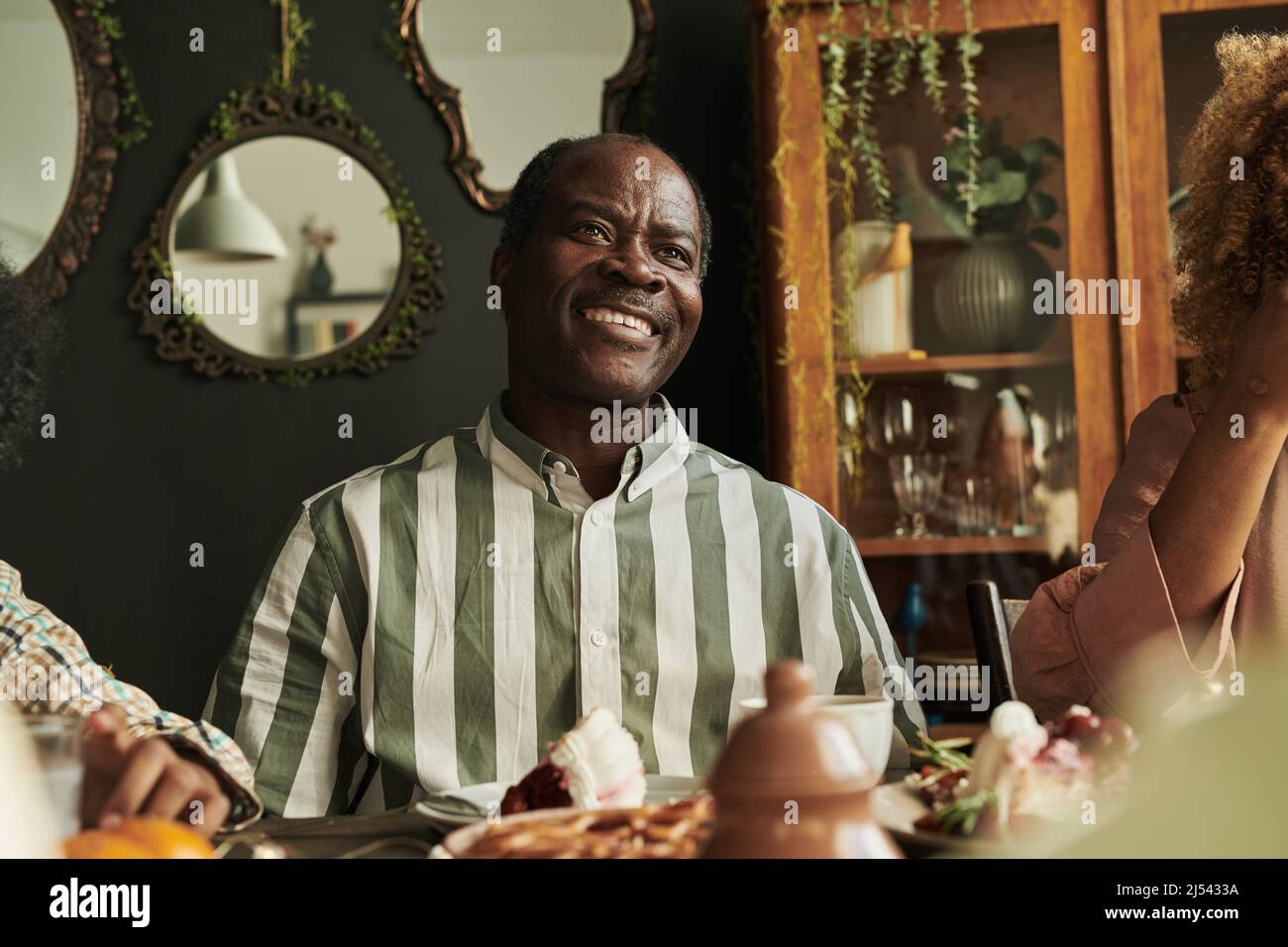 Happy grandfather sitting at table and smiling while eating dessert ...