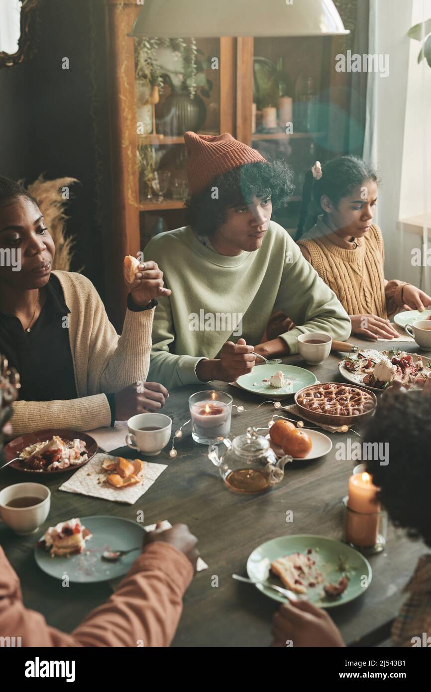 African family sitting at dining table eating homemade pie and drinking ...