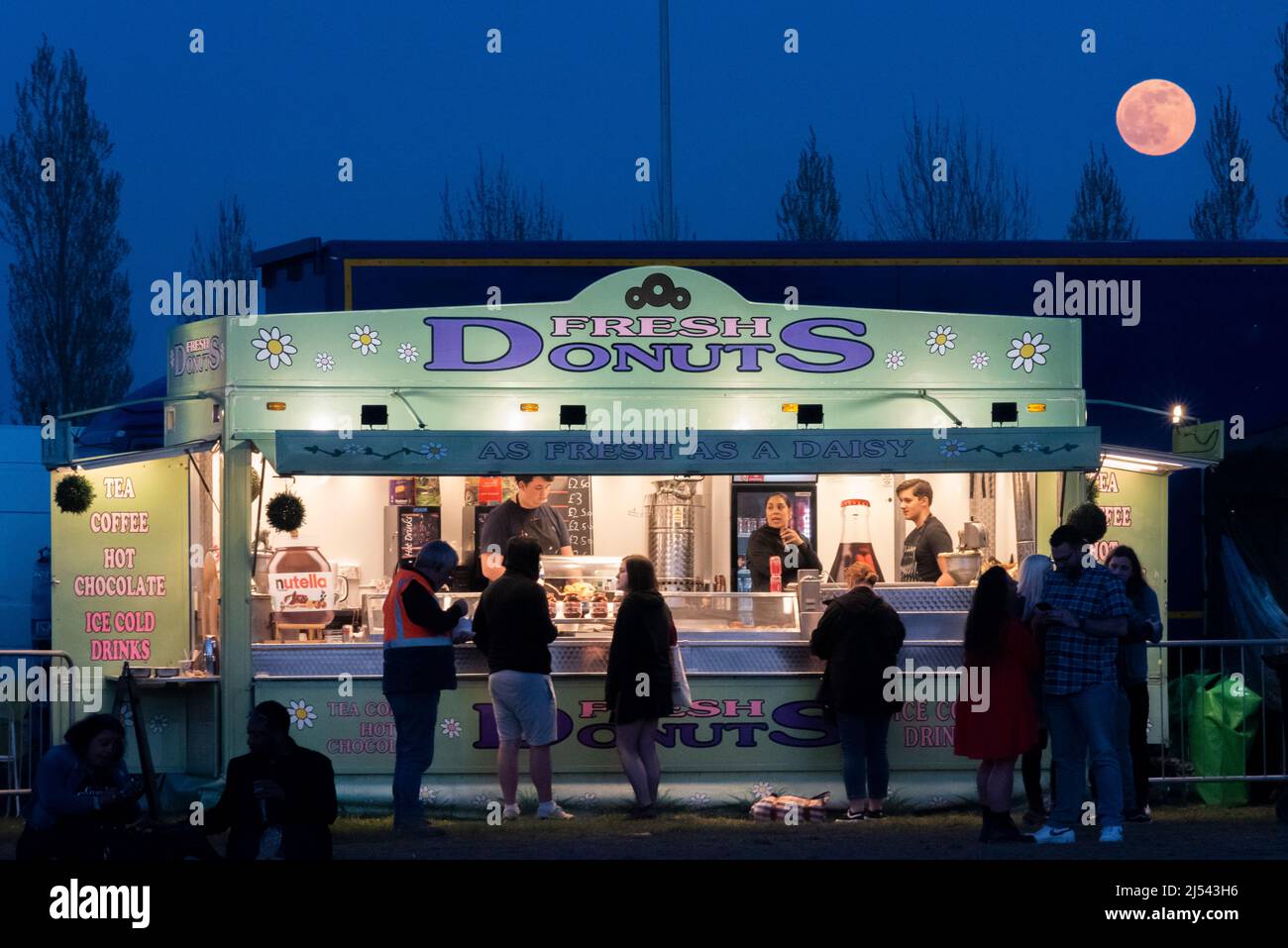 Pink moon rising over a fresh donuts vendor at an outside 1980s retro ...