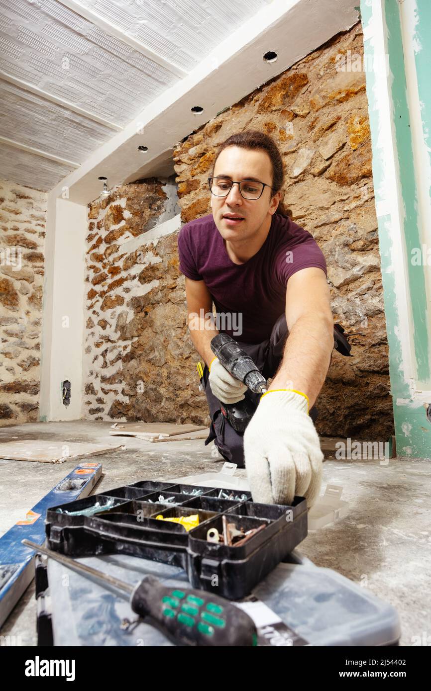 Worker man with screwdriver takes screws from box Stock Photo - Alamy