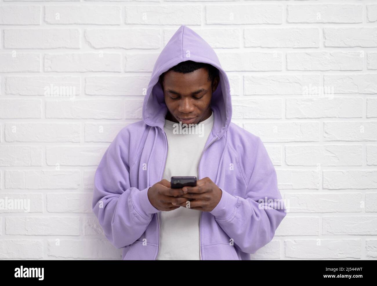 Black young man using smartphone over white brick background, finger ...