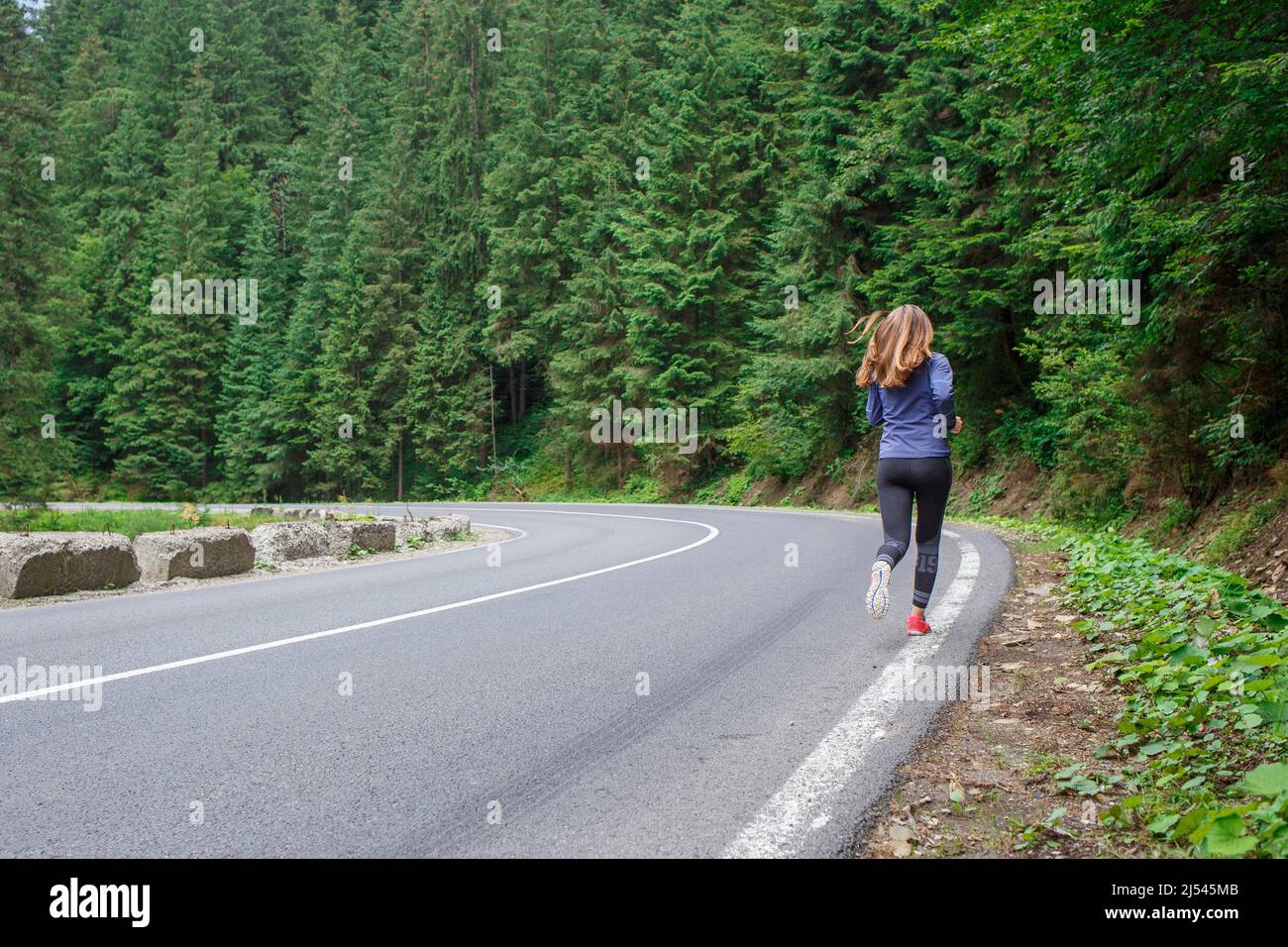 Runner woman running on the mountain road through the forest Stock ...