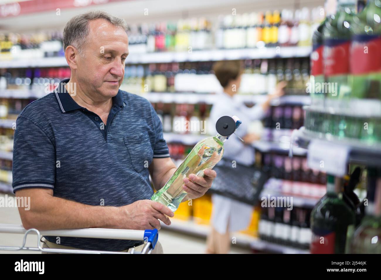 elderly retired man buying wine in the alcohol section of the ...
