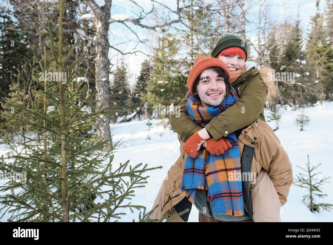 Joyful young man in love giving his girlfriend piggyback ride while ...