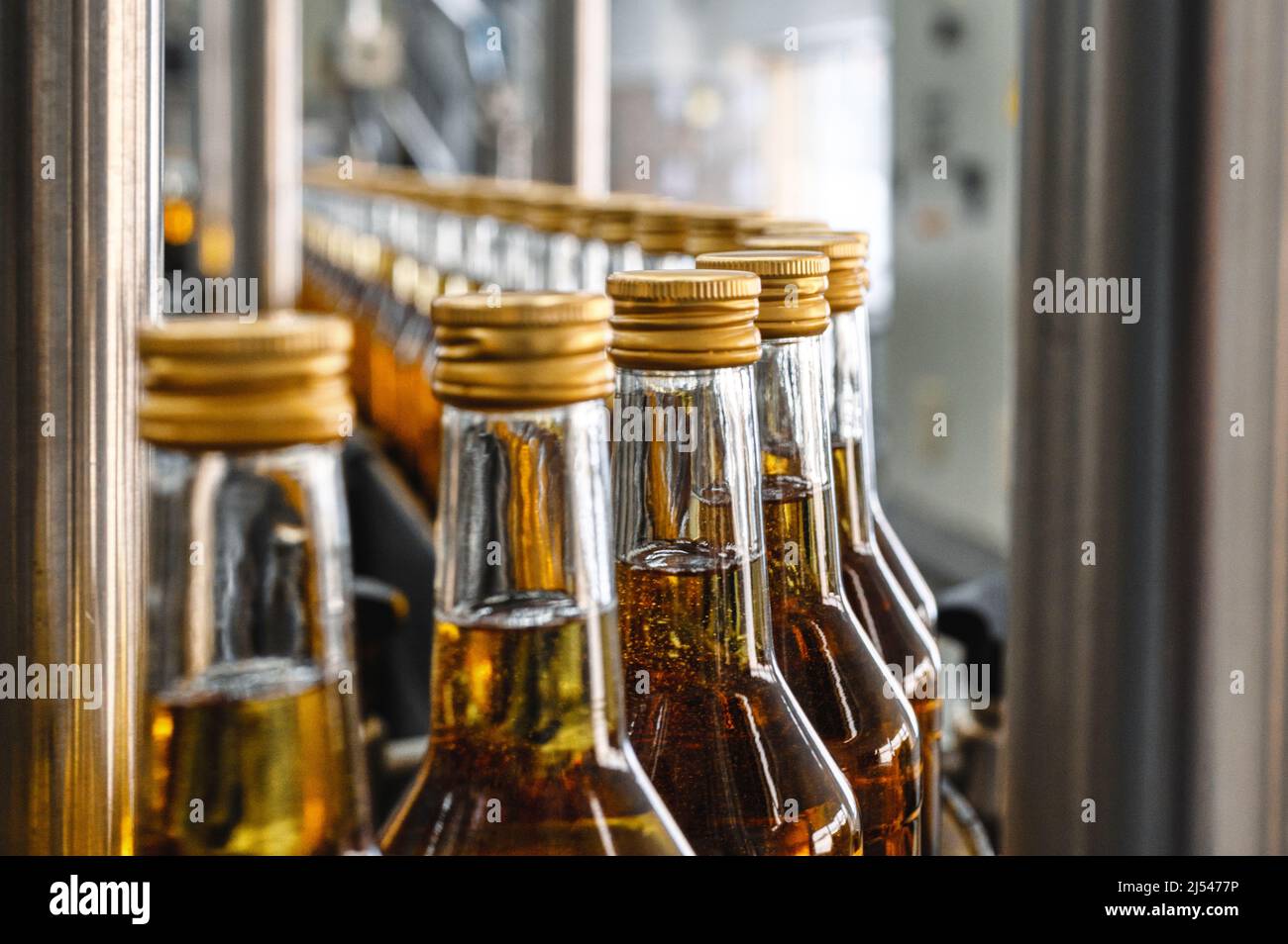 Bottles of golden alcohol with caps transported by conveyor Stock Photo ...