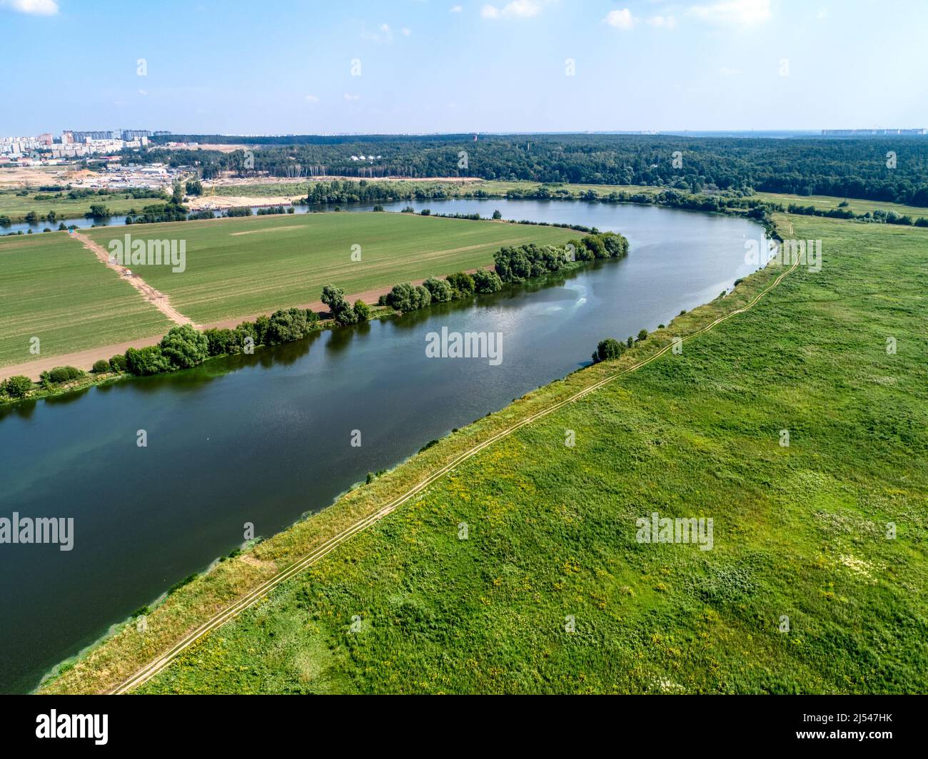 Large green field and trees near tranquil river in spring Stock Photo ...