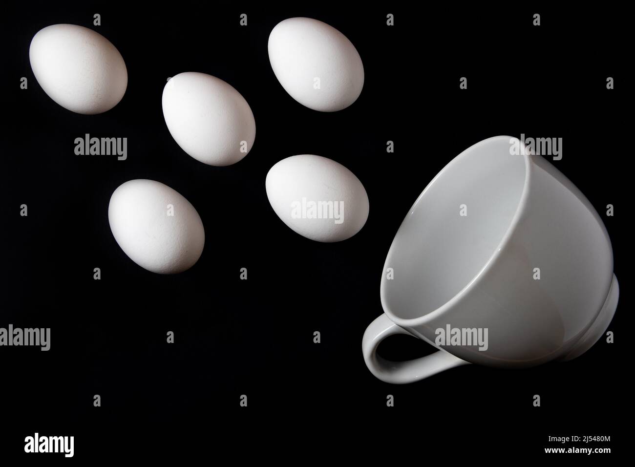 White chicken eggs and a big white cup over black background Stock ...
