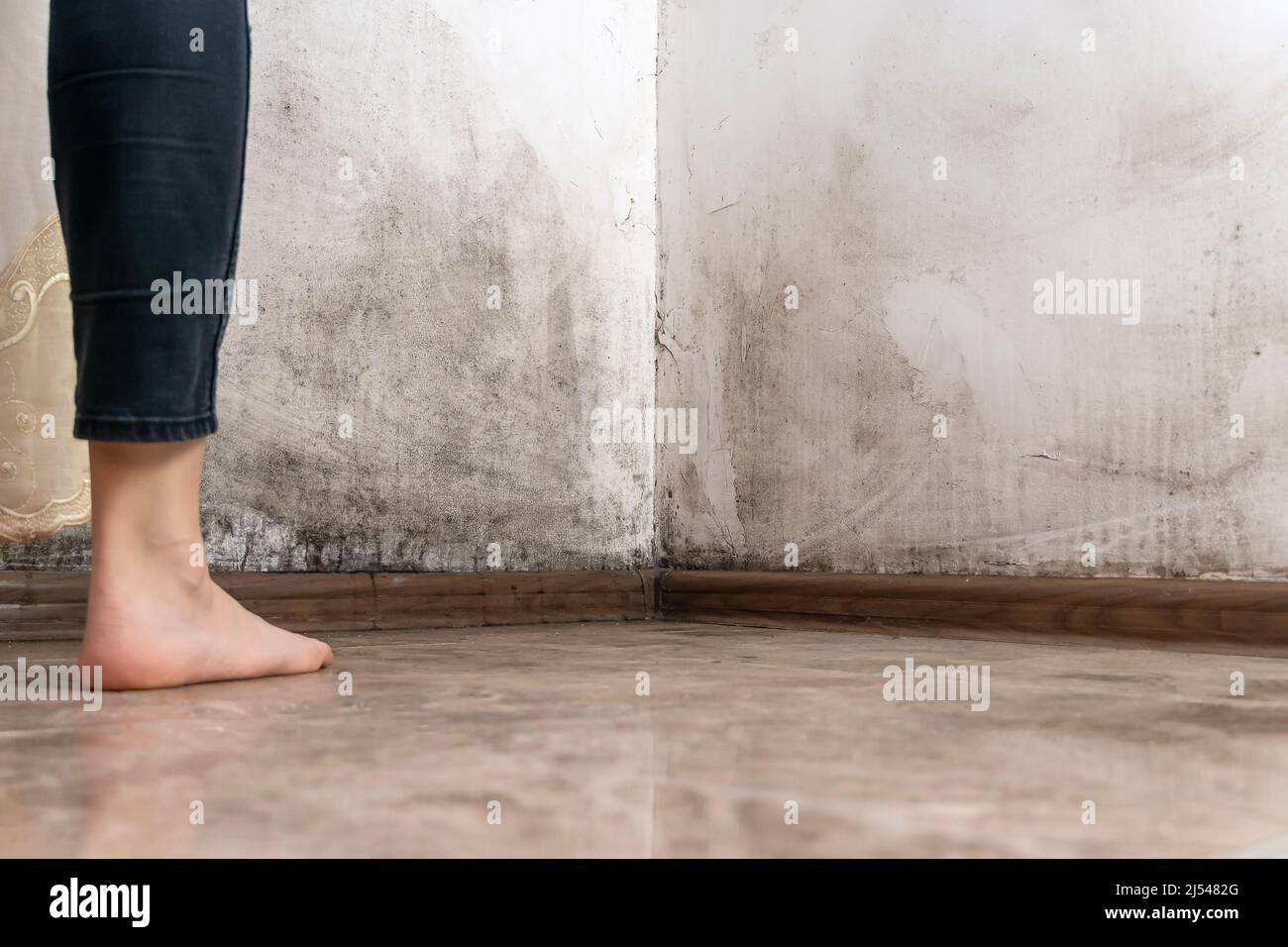 Close-up of a woman's legs standing near a white wall with mold Stock ...
