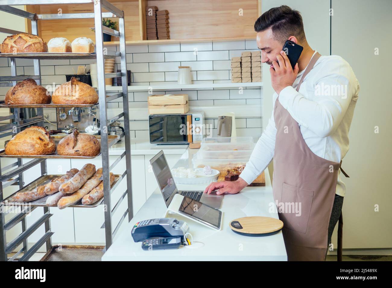 Handsome baker in uniform at the manufacturing small business owner ...