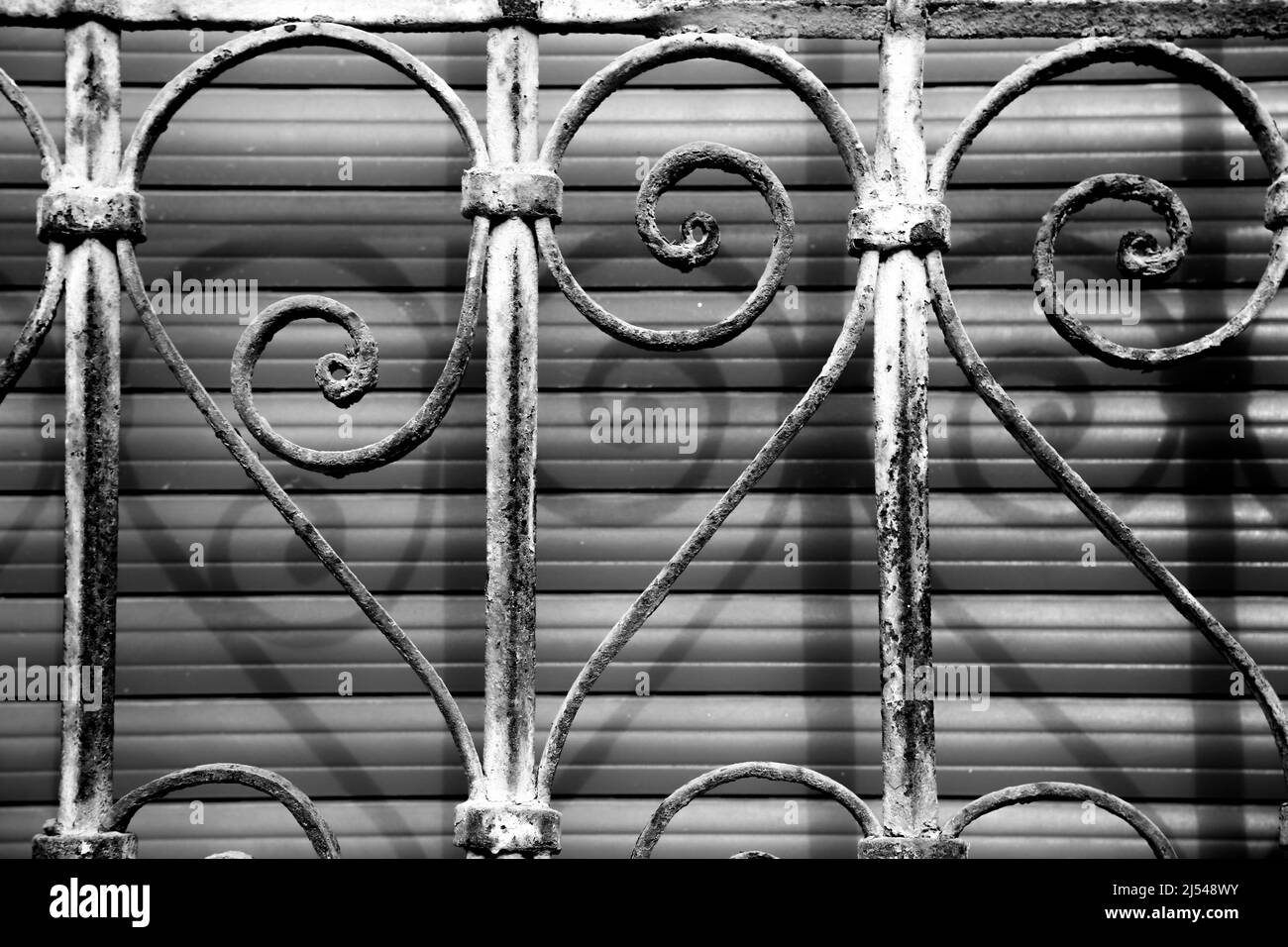 Window with forged metal lattice with curved details and wooden blind ...
