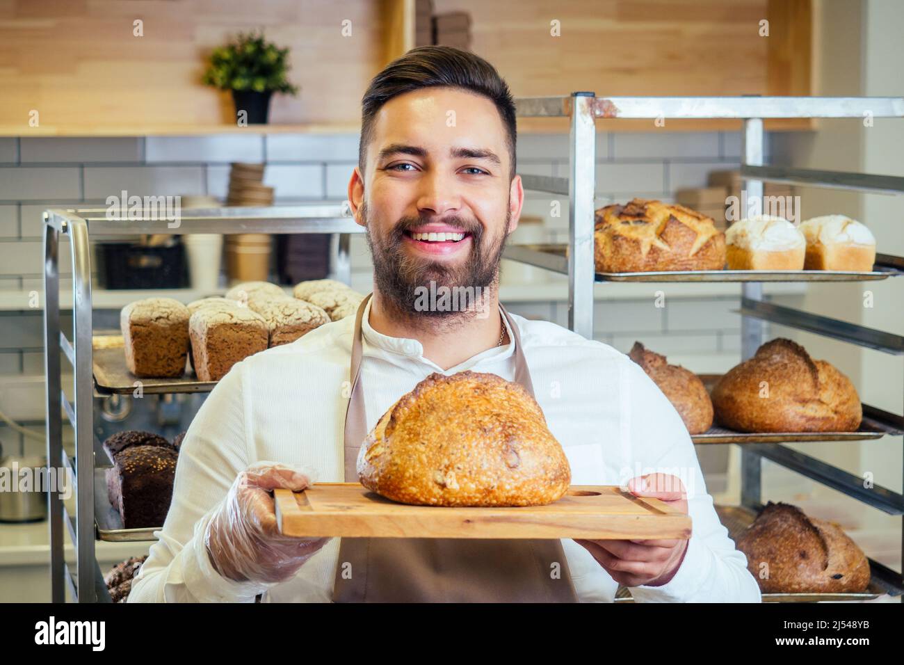 Handsome baker in uniform at the manufacturing small business owner ...