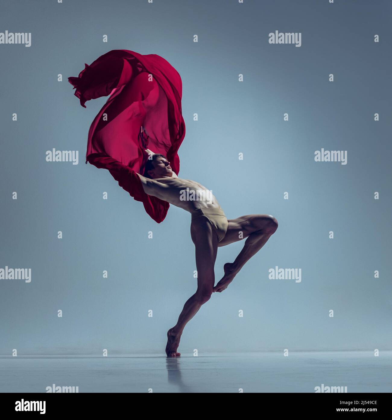 Portrait of young man, flexible ballet dancer in action with red fabric ...