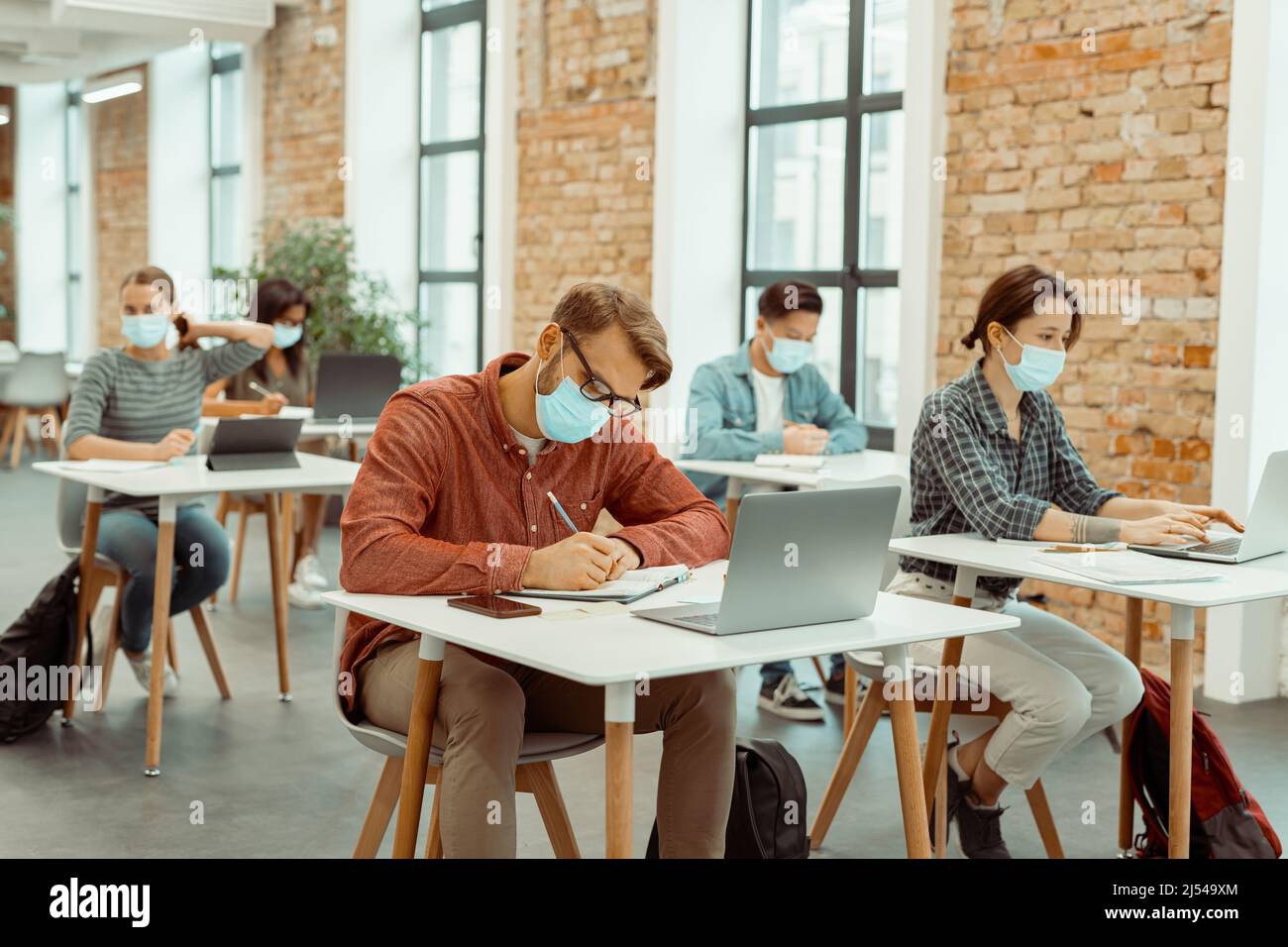 Multi ethnic students are writing in notebooks Stock Photo - Alamy