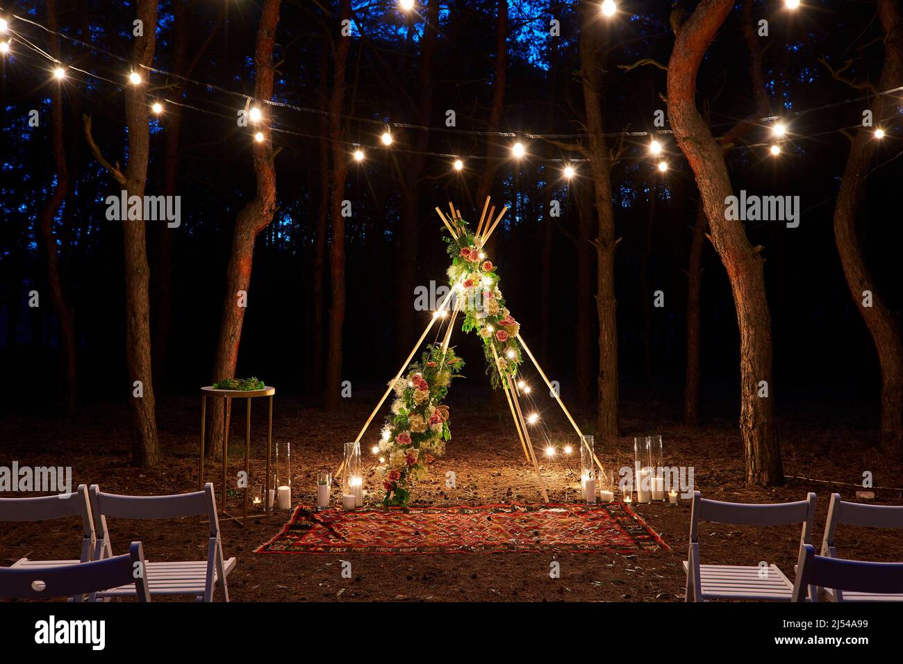 Festive string lights illumination on boho tipi arch decor on outdoor ...