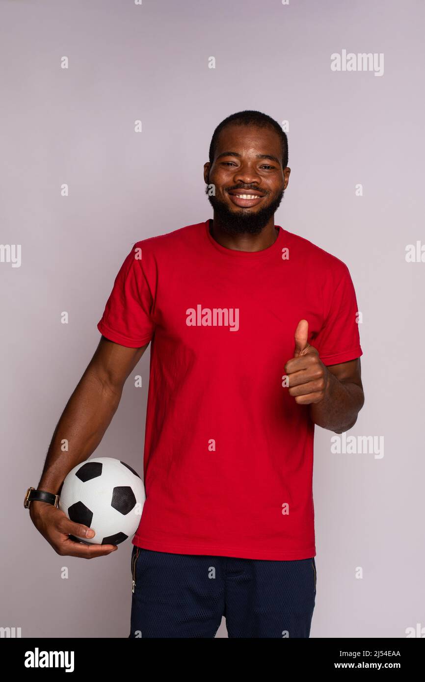 african man who is a football fan holding a ball Stock Photo - Alamy