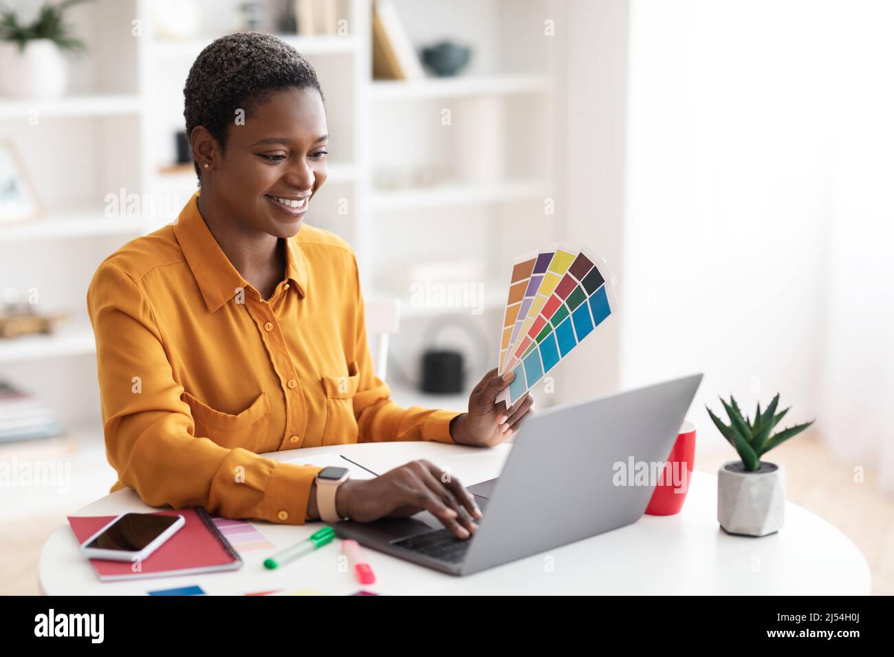 Joyful black lady working as web designer, office interior Stock Photo ...