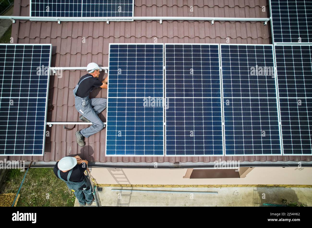 Men technicians mounting photovoltaic solar moduls on roof of house ...