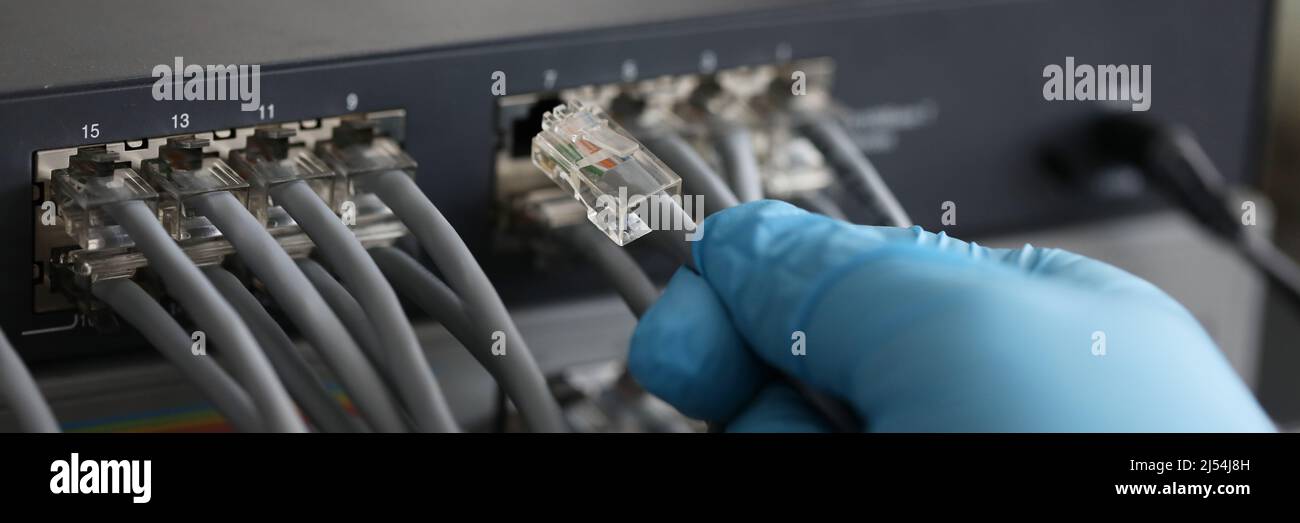 Person working in network server room with fiber optic hub for digital ...