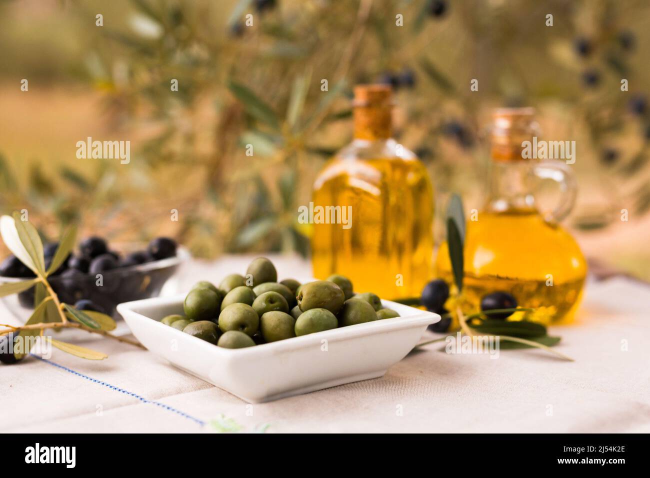 green ripe olives, olive oil in a glass traditional bottle on a table ...